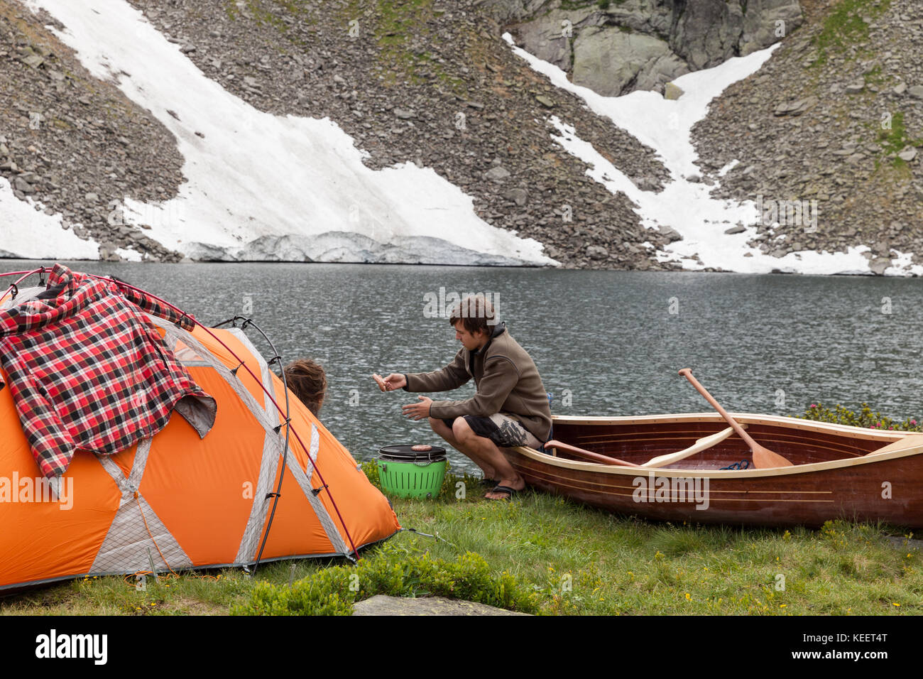 Couple on the lake shore with canoe, grilled meat Stock Photo - Alamy