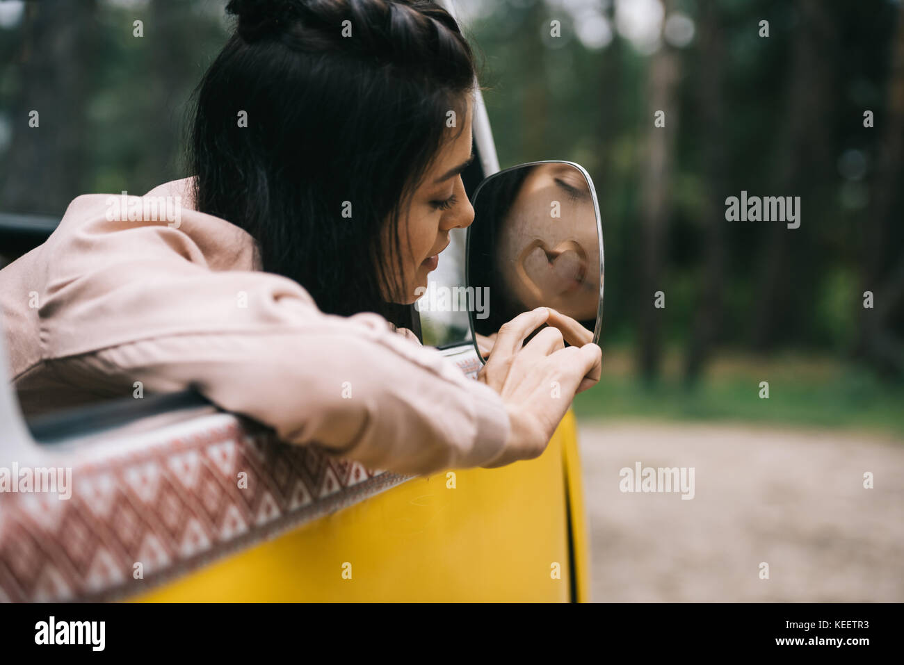 attractive young girl drawing heart sign on mirror of retro minivan ...