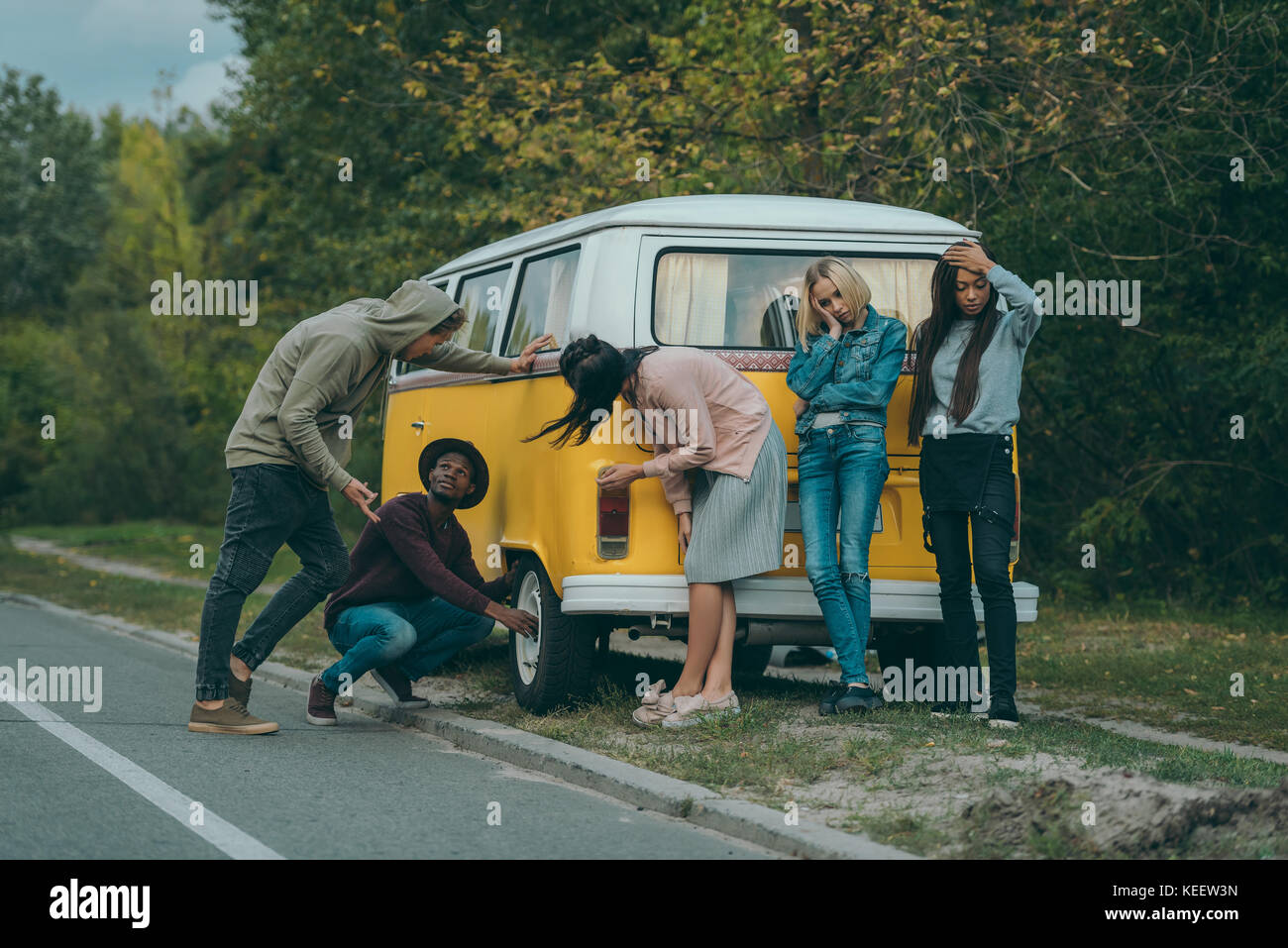 multiethnic friends standing near broken minivan on road Stock Photo ...