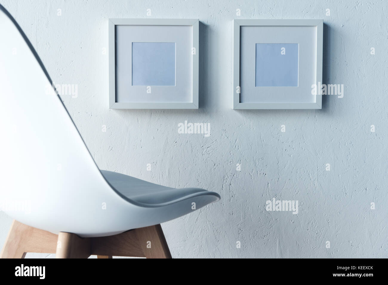 close up view of empty photo frames hanging on wall and chair standing ...