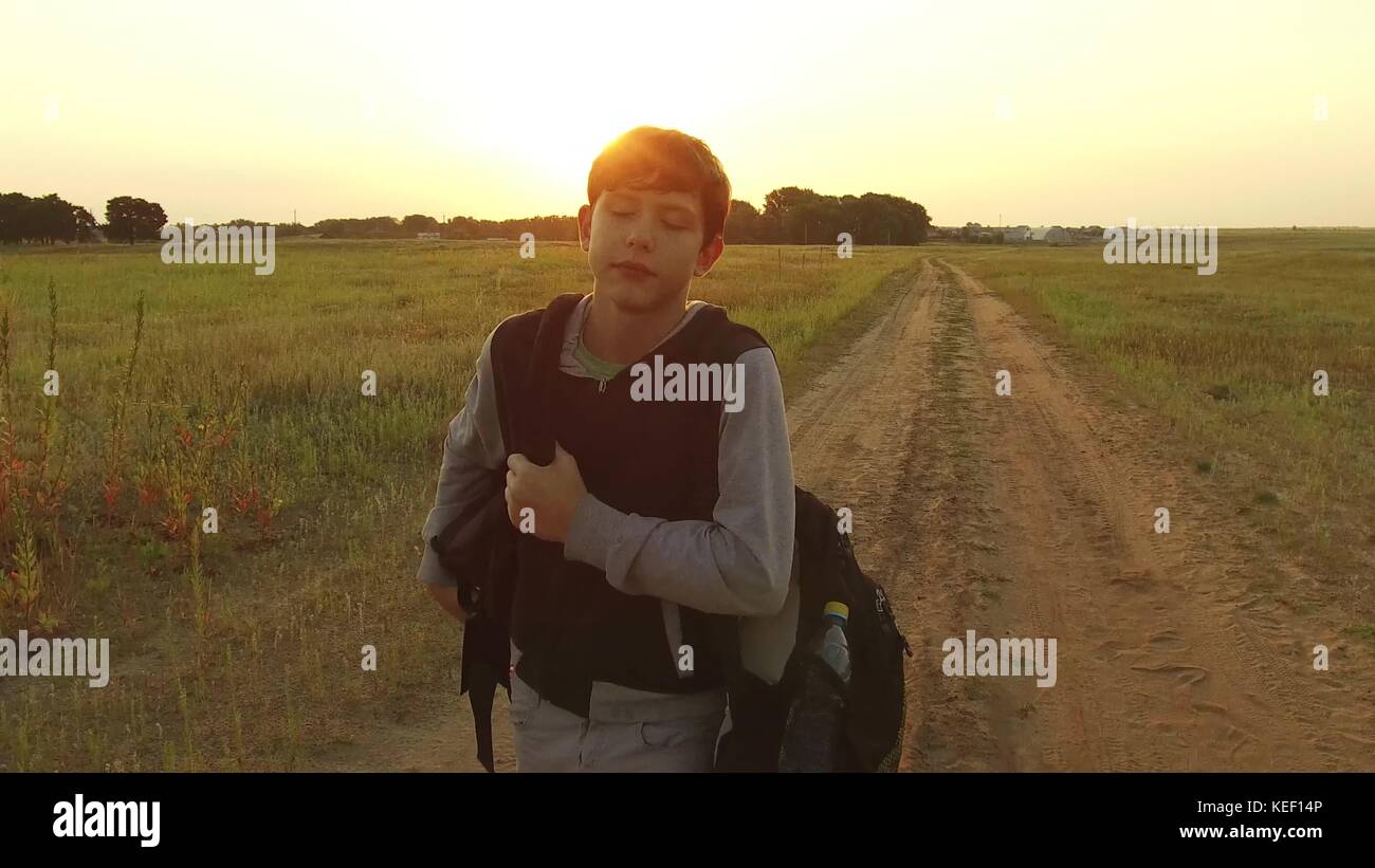 Boy teen traveling. Boy teenage tramp walking along the road in hood ...