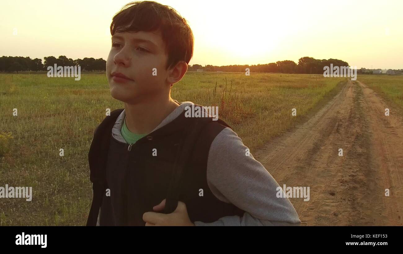 Boy teen traveling. Boy teenage tramp walking along the road in hood ...