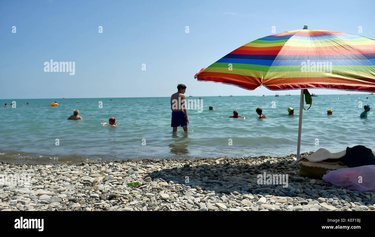 People bathing in the sun, swimming and playing games on the beach ...