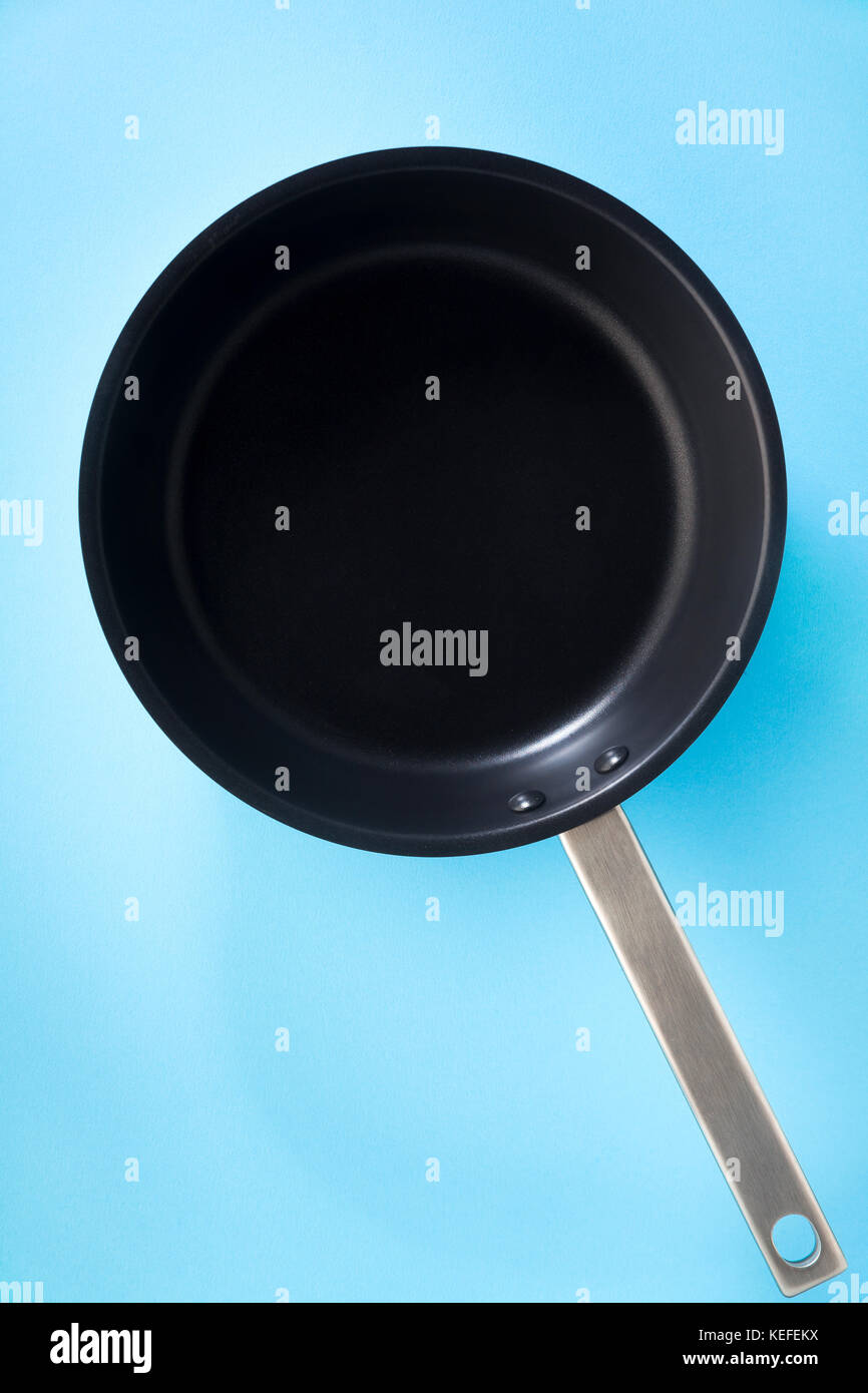 empty pan with non-stick coating and a steel pen isolated on blue Stock ...