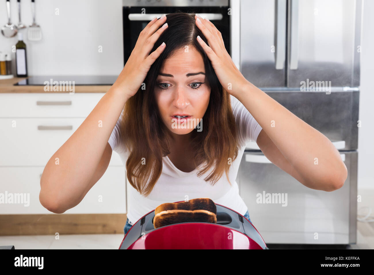 Young Frustrated Woman Looking At The Slice Of Burnt Toast Coming Out ... Young Frustrated Woman Looking At The Slice Of Burnt Toast Coming Out ...