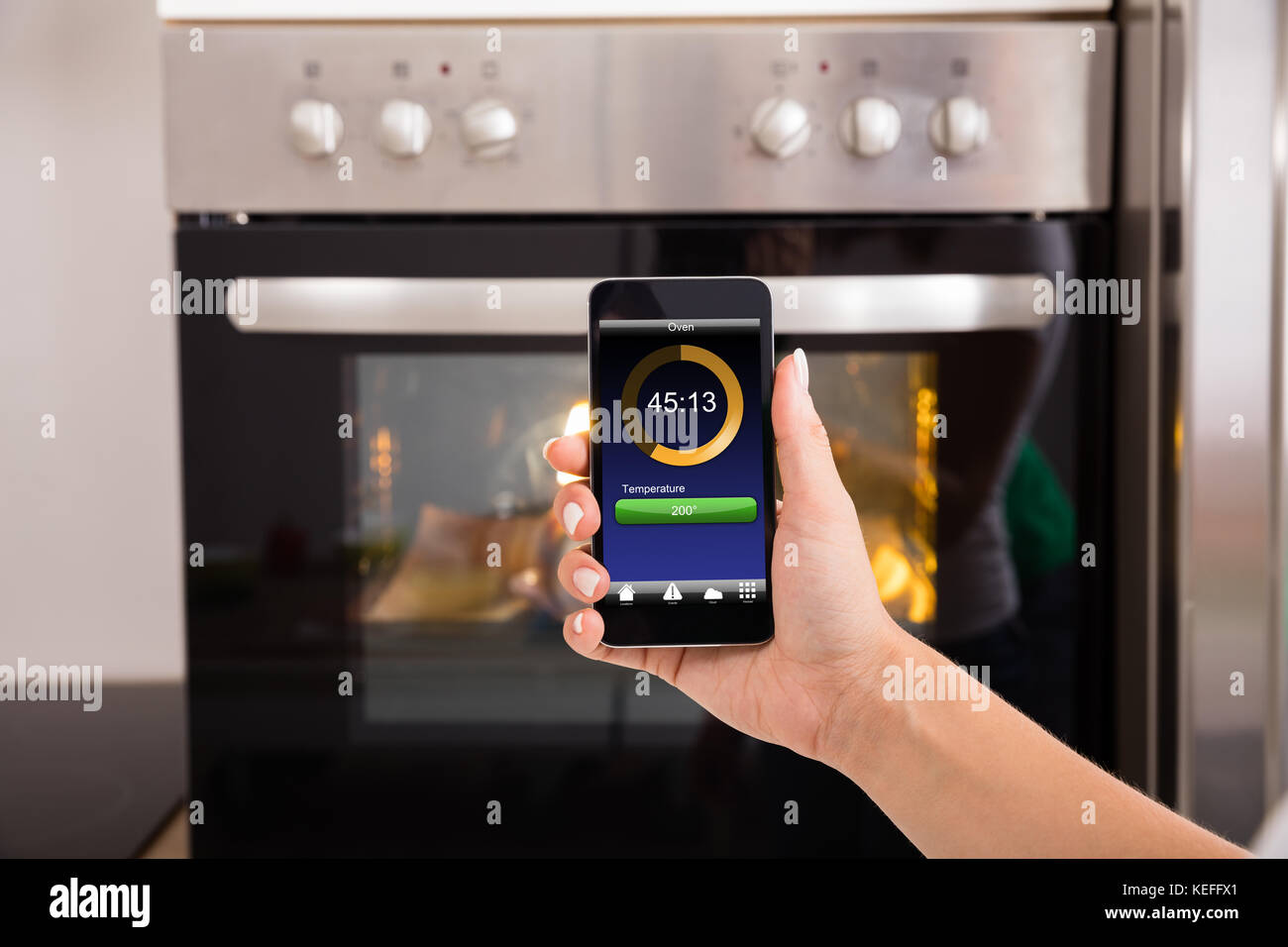 Close-up Of Person Hands Operating Oven Appliance With Mobile Phone ...