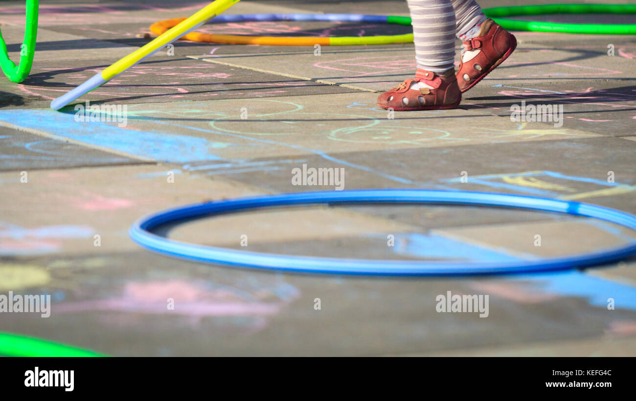 Small girl play hula hoops on playground scratched with chalk Stock ...