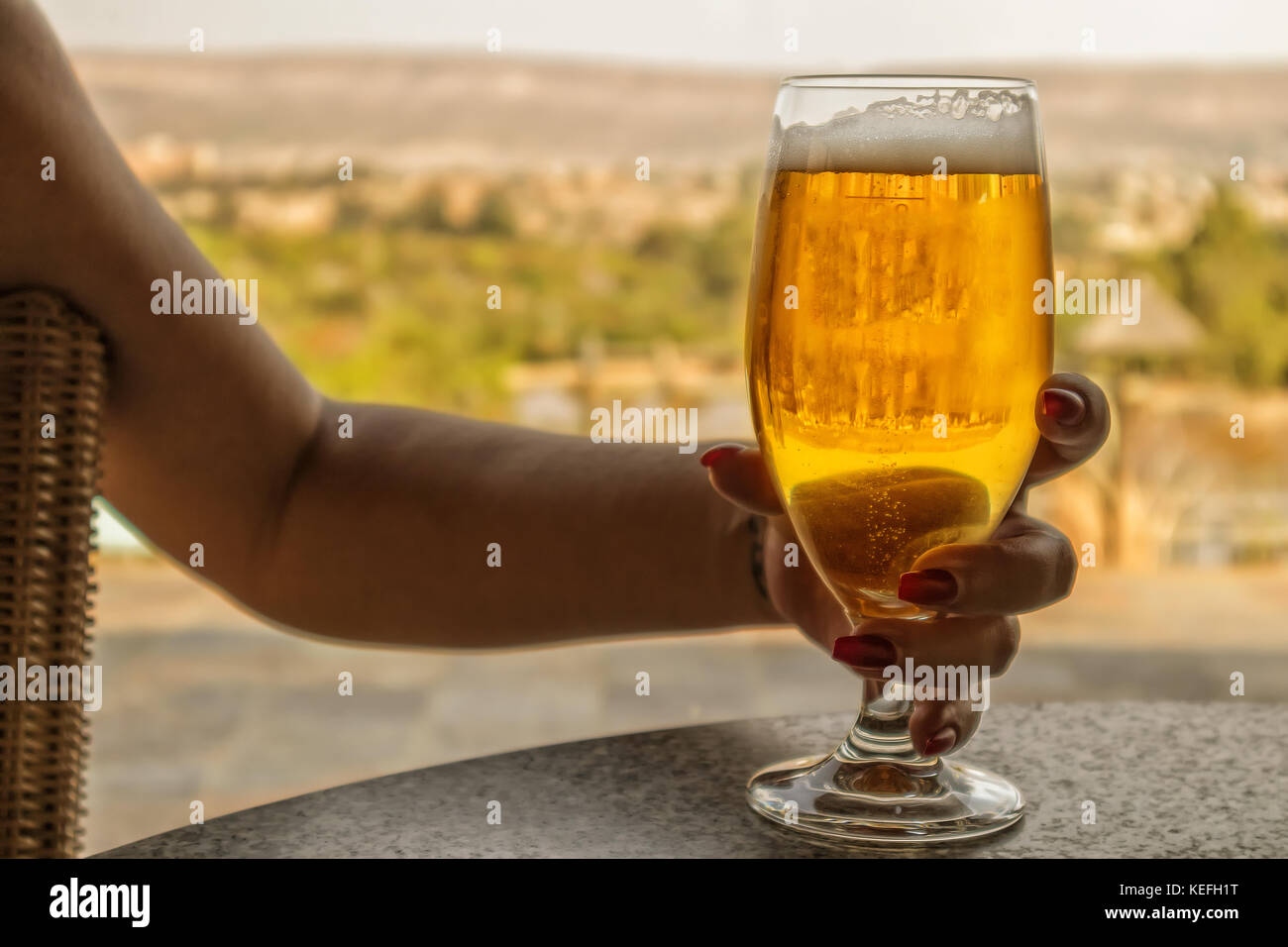 Woman's hand grab a glass of beer, with nature in blurred background ...