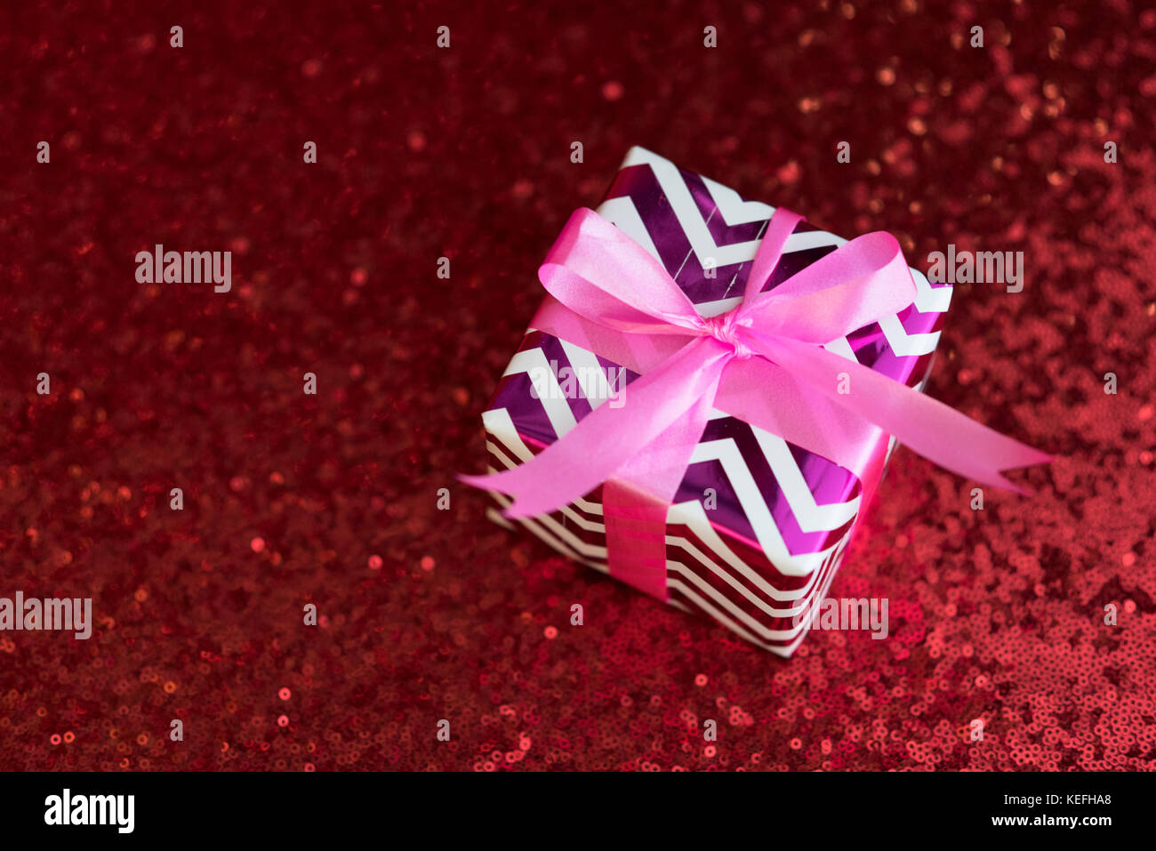 gift / present on a red sequin cloth Stock Photo - Alamy