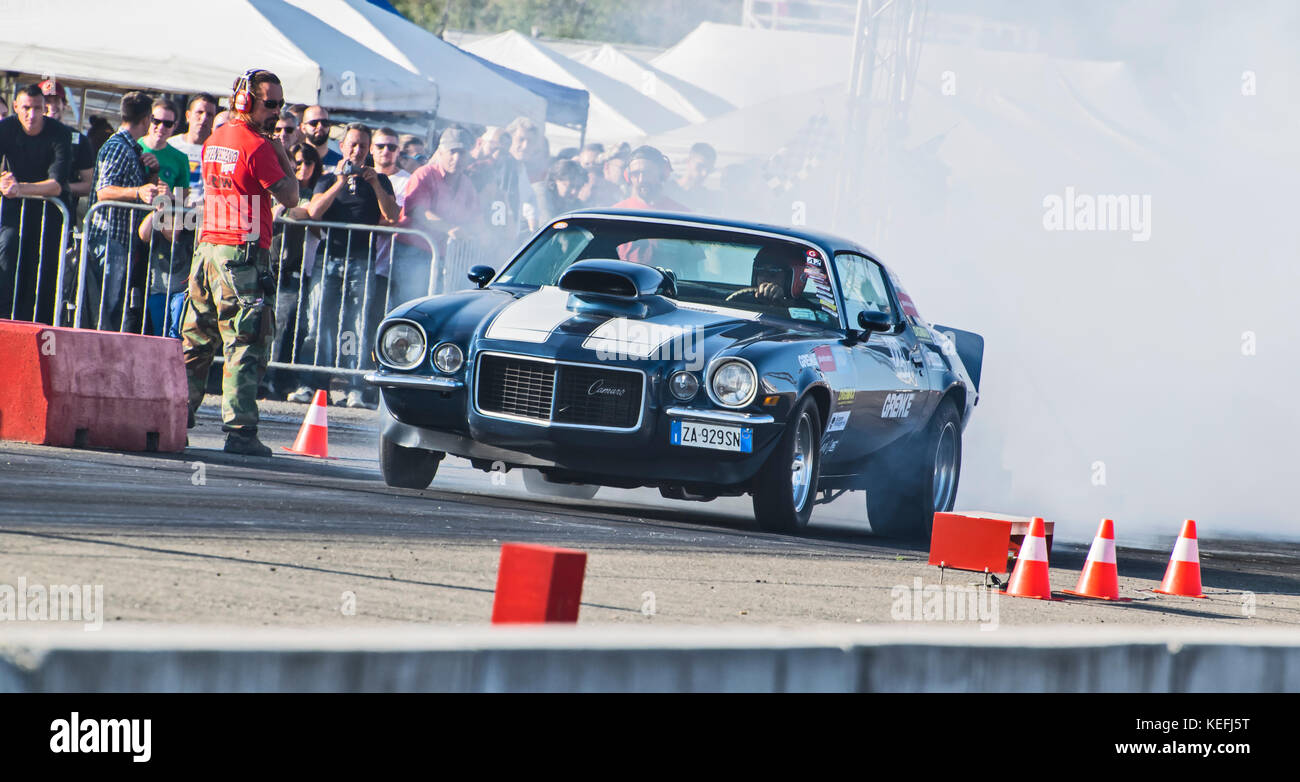 a blue camaro muscle car on the start line of a dragway at a motor show ...