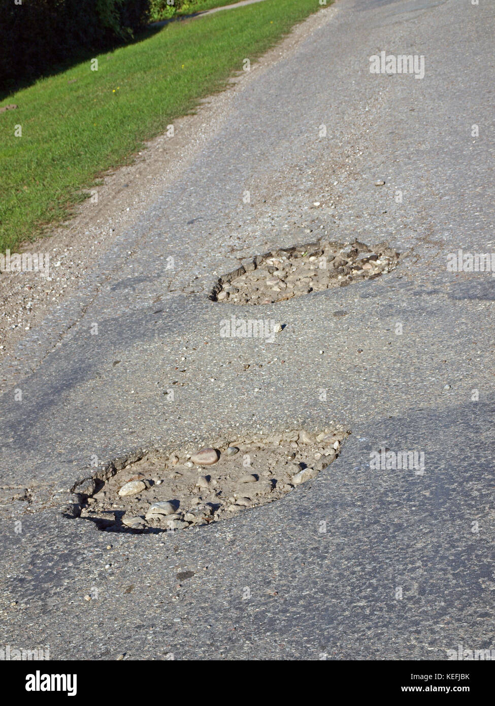 Unsafe road with deep holes in asphalt pavement Stock Photo - Alamy
