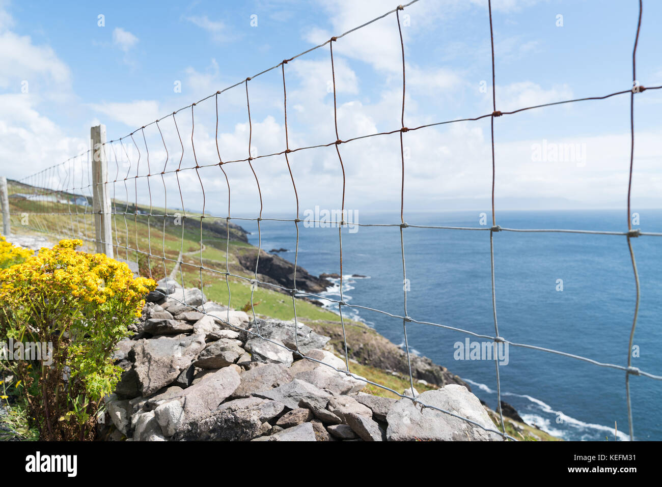 Wire mesh fence along low rock wall above rocky cliffs along Wild ...