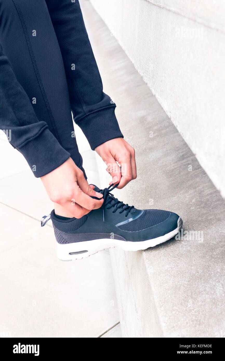 MODEL RELEASED. Woman tying trainers with foot on step Stock Photo - Alamy