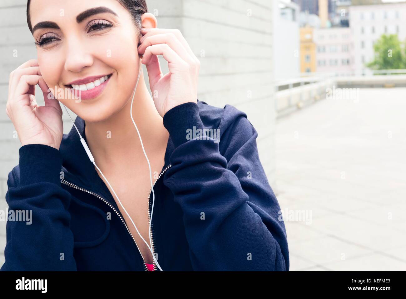 MODEL RELEASED. Young woman wearing earphones, smiling Stock Photo - Alamy