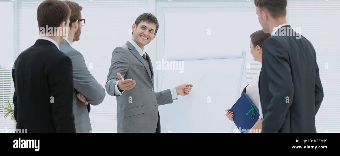 in the middle of the office Manager with pen in hand, shows a poster ...