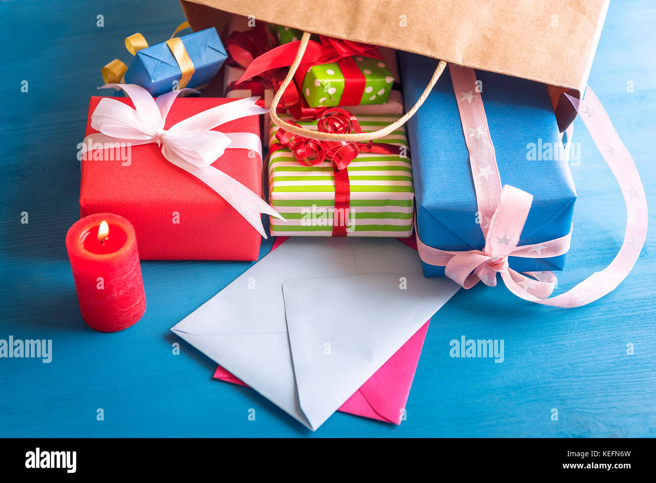 Many and colorful presents spilled out of a bag on a blue wooden table ...