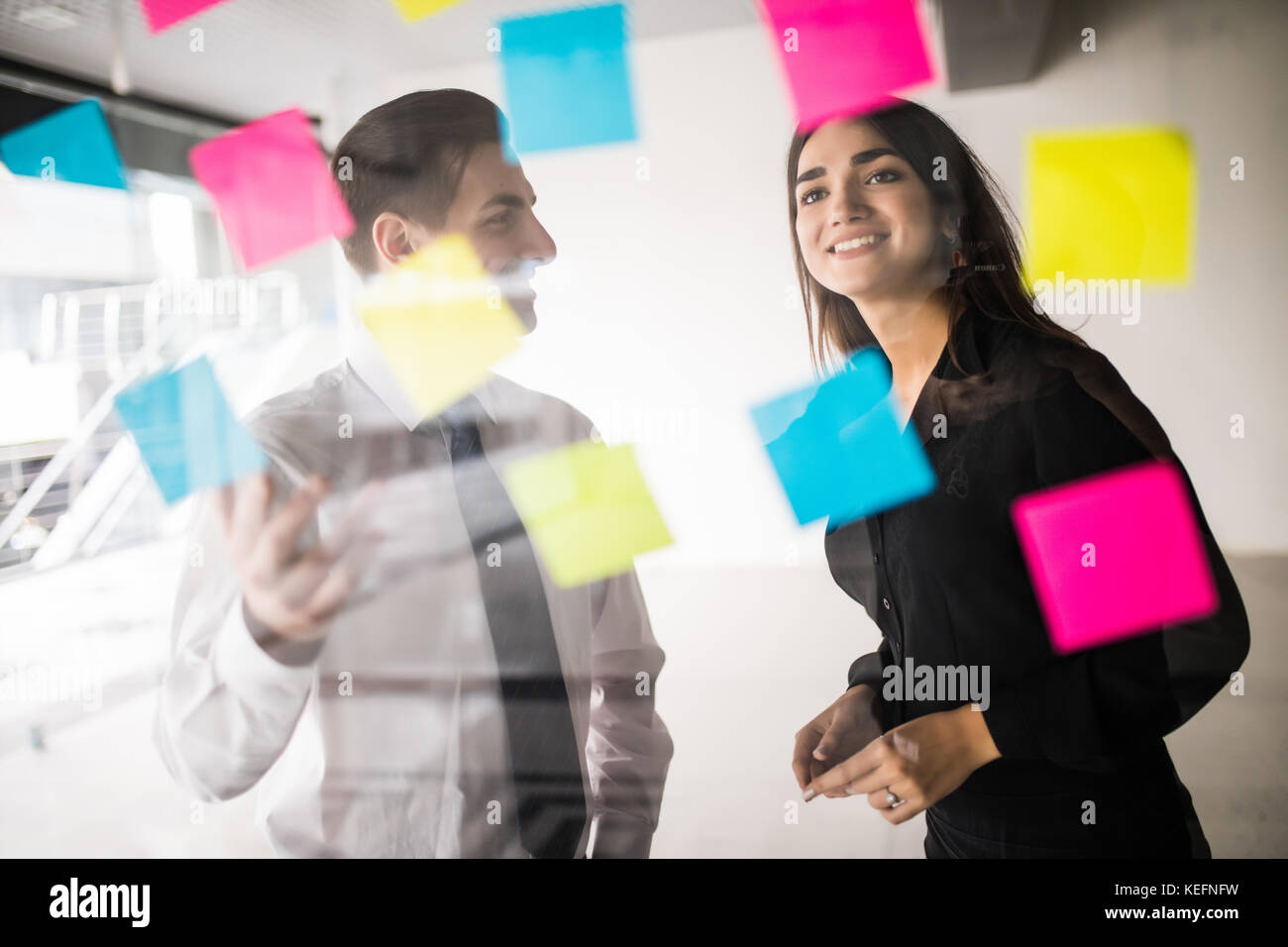 happy creative team writing on stickers at office glass board Stock ...