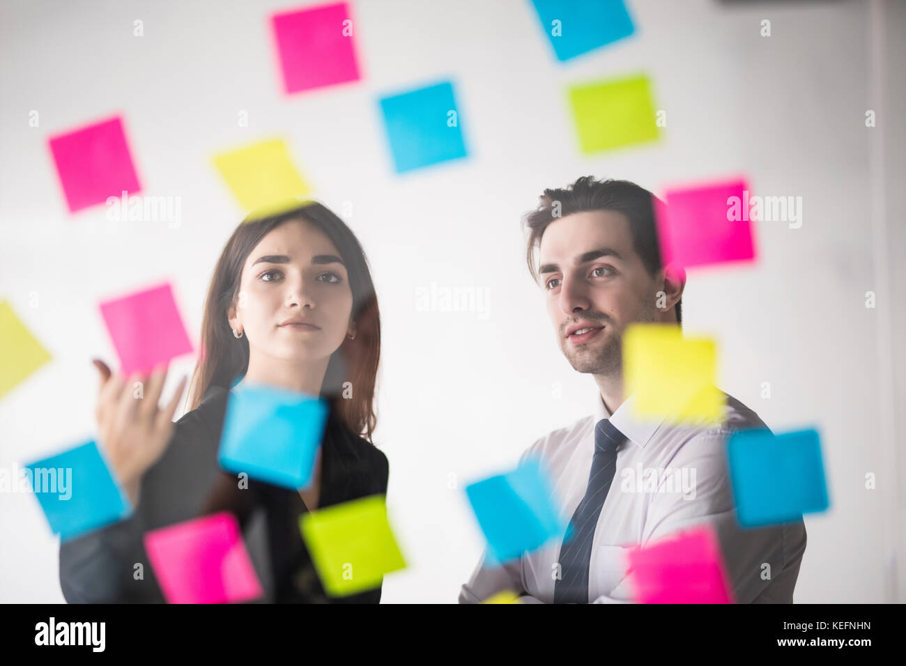 happy creative team writing on stickers at office glass board in modern ...