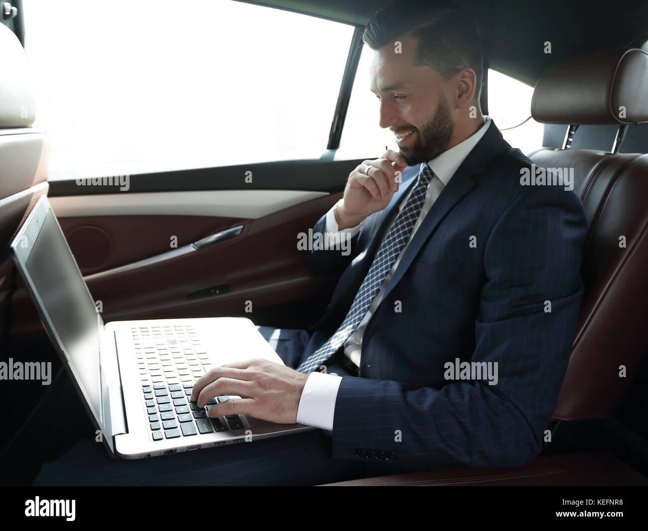Businessman typing text on laptop while sitting in car Stock Photo - Alamy