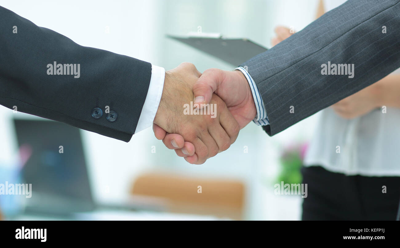 Good deal. Close-up of two business people shaking hands while sitting at the working place ...