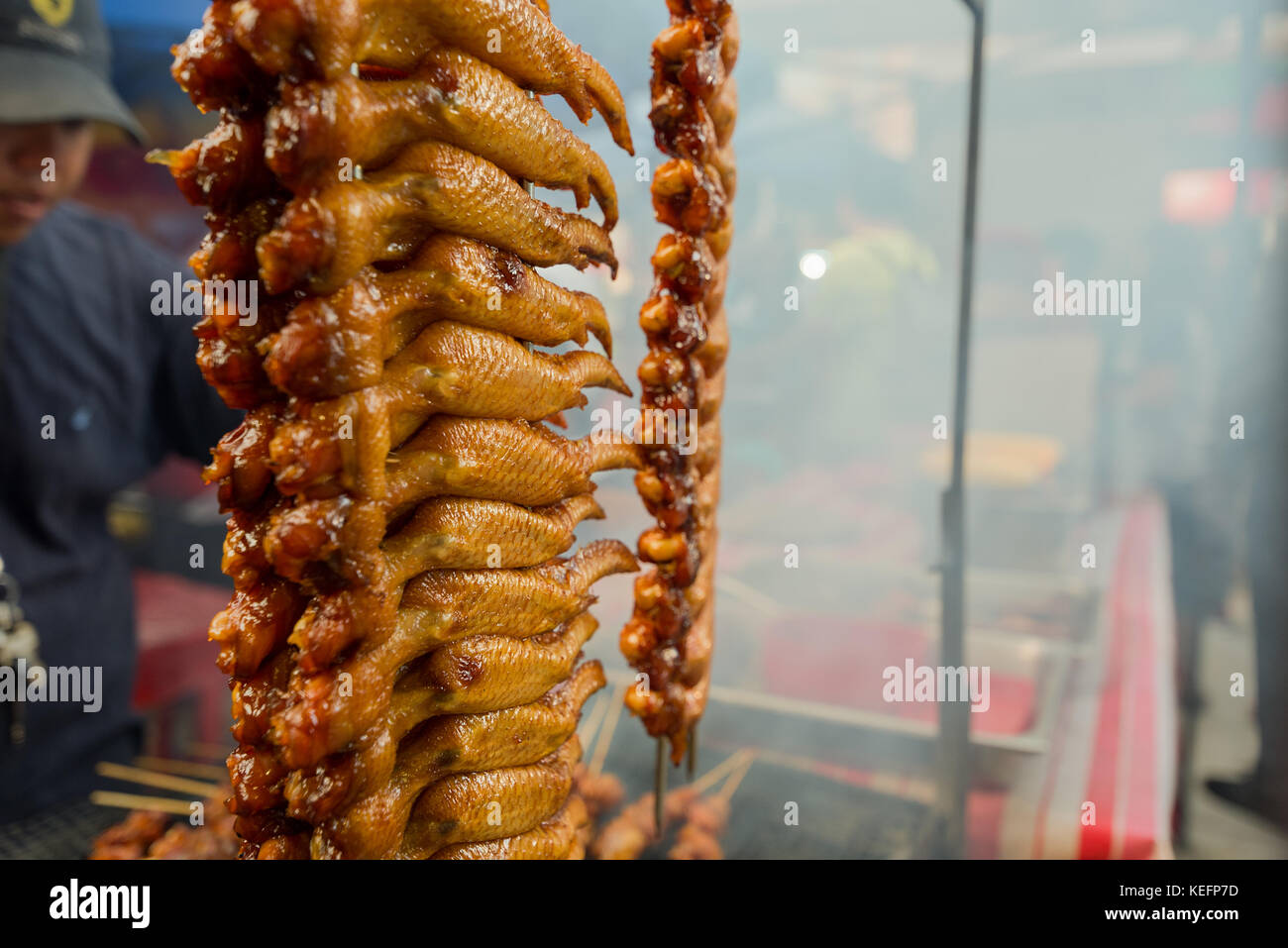 Cooked and glazed chicken wings on a skewer on a street food stall in ...