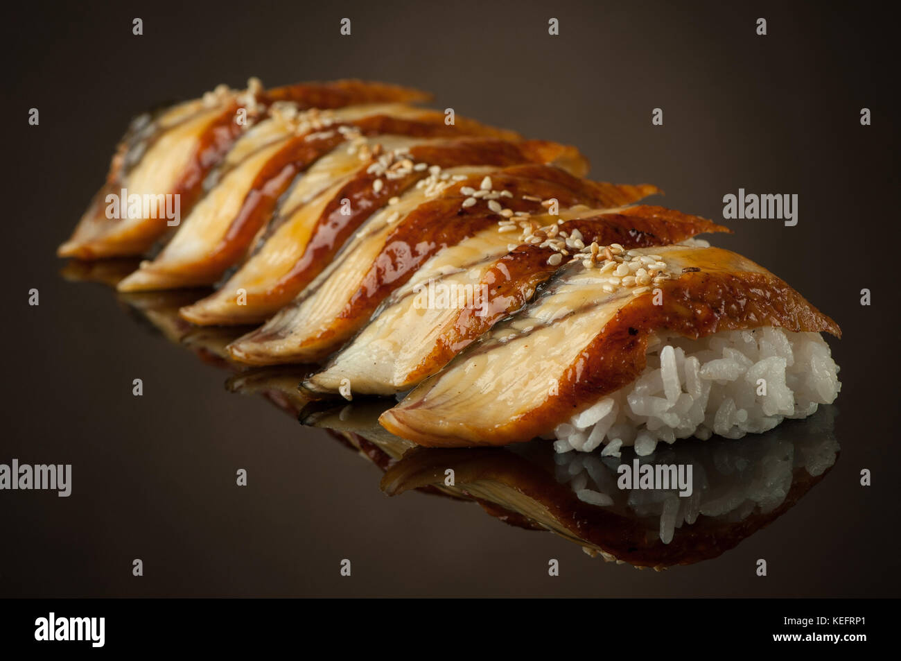 sushi with rice and sesame seeds on a dark background with reflection ...