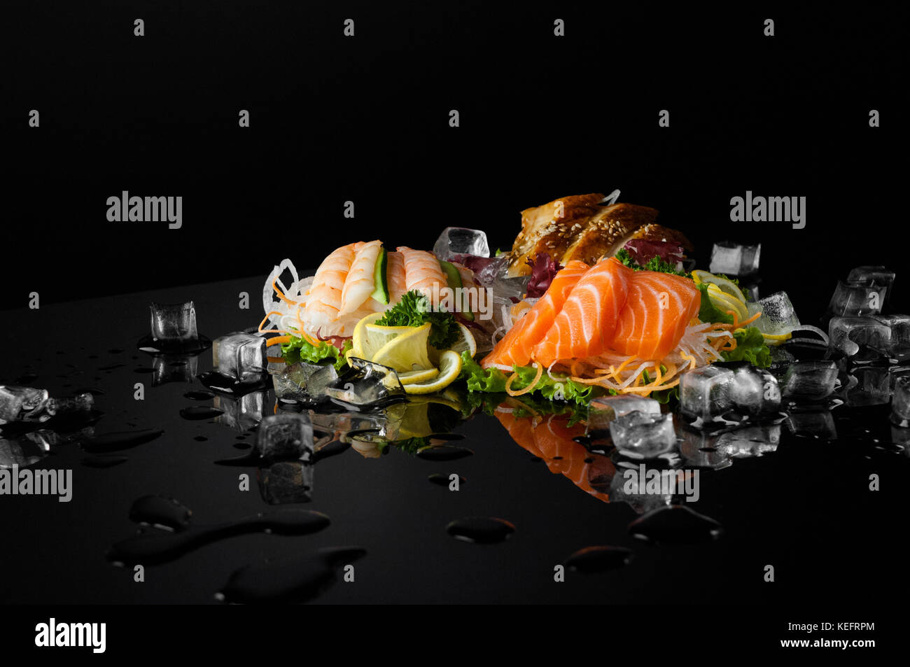 a variety of sushi with pieces of melting ice on a black background ...