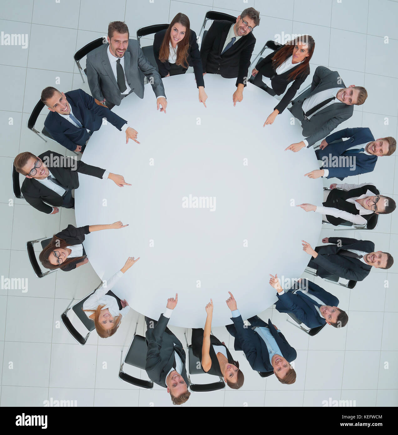 Diverse group pf young business people seated round a table discussing ...