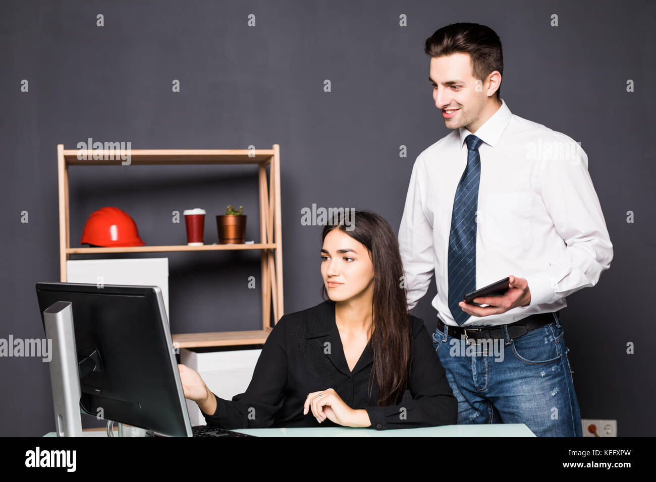 Young design team working at desk looking at computer in creative ...