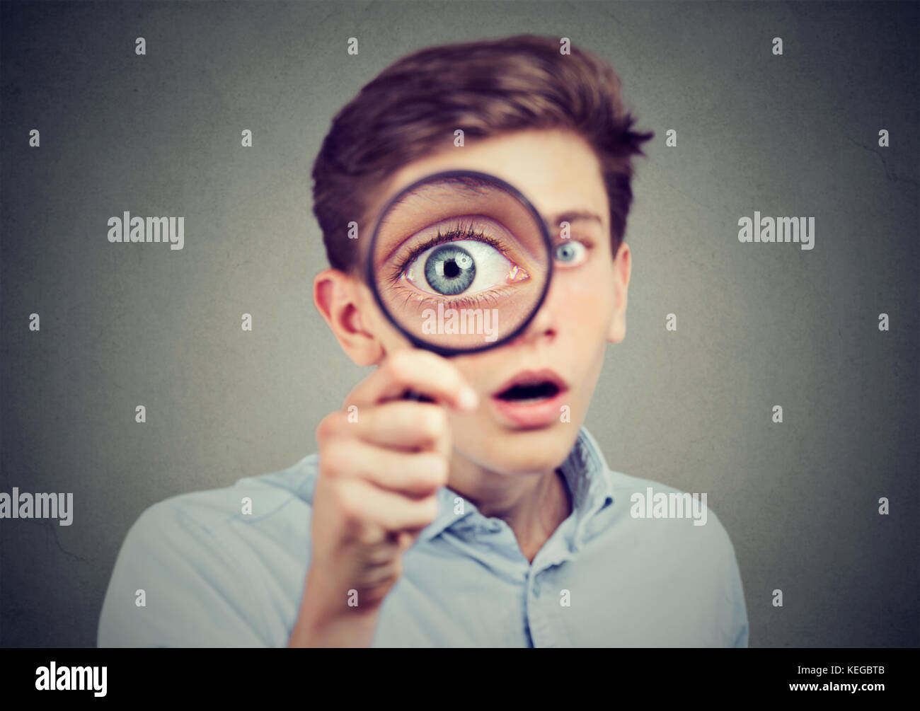 Curious amazed young man looking through a magnifying glass Stock Photo ...