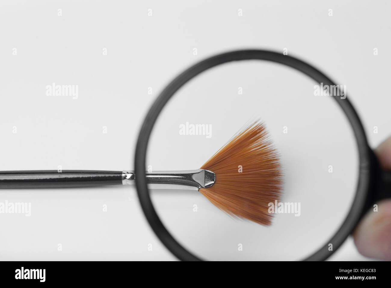 Brush on a white background with a magnifying glass Stock Photo - Alamy