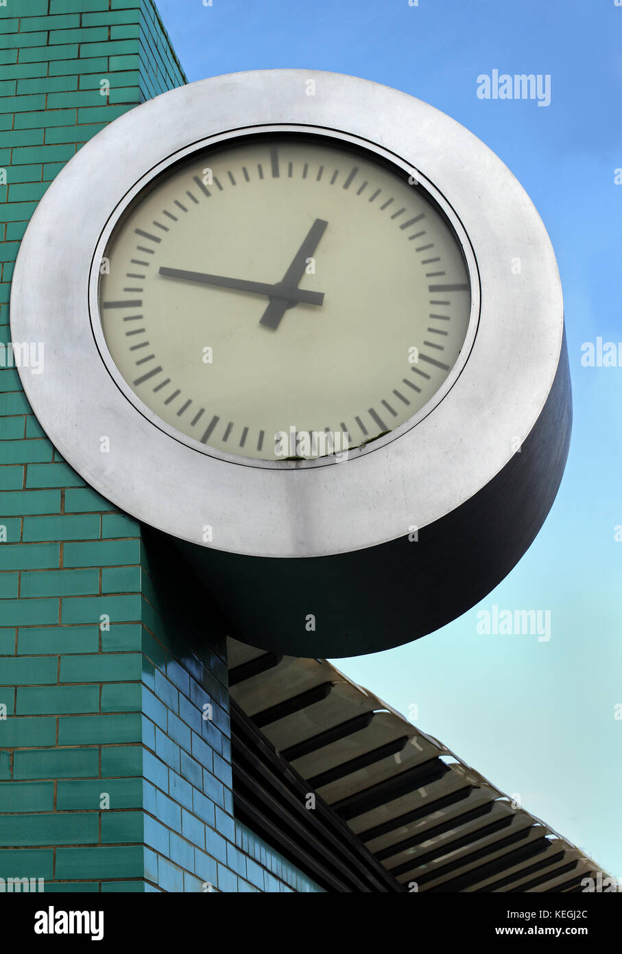 Public clock hanging from green facade building Stock Photo - Alamy