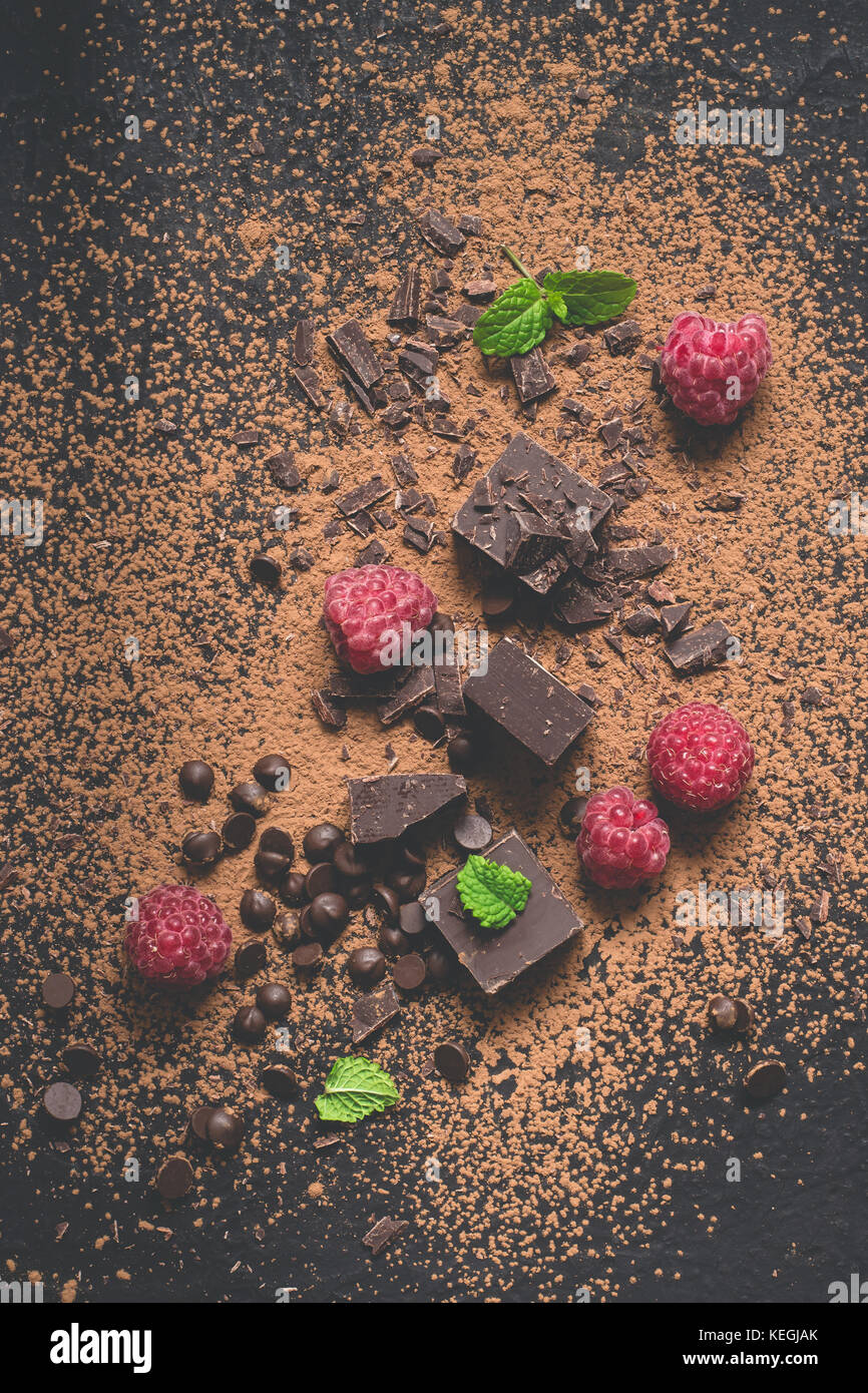 Pieces of dark chocolate, powder, drops and raspberries. Food dessert ...