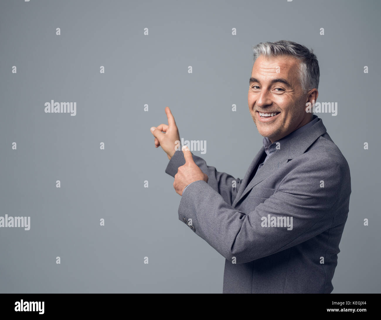 Confident smiling businessman pointing at blank copyspace, advertising ... Confident smiling businessman pointing at blank copyspace, advertising ...