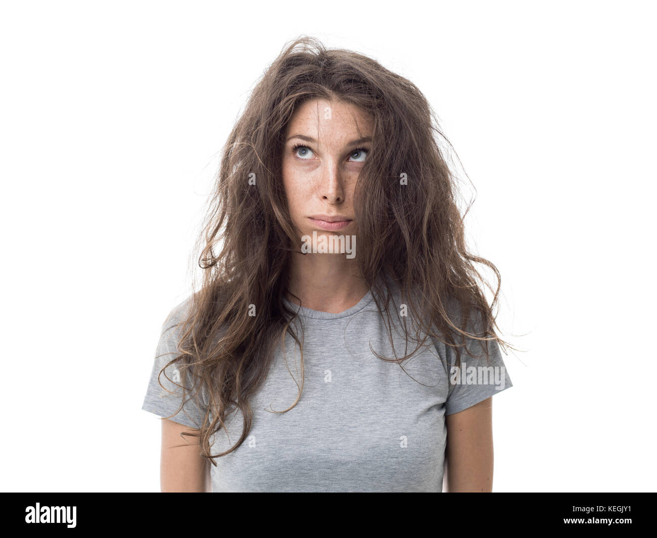 Angry young woman having a bad hair day, her long hair is messy and ...