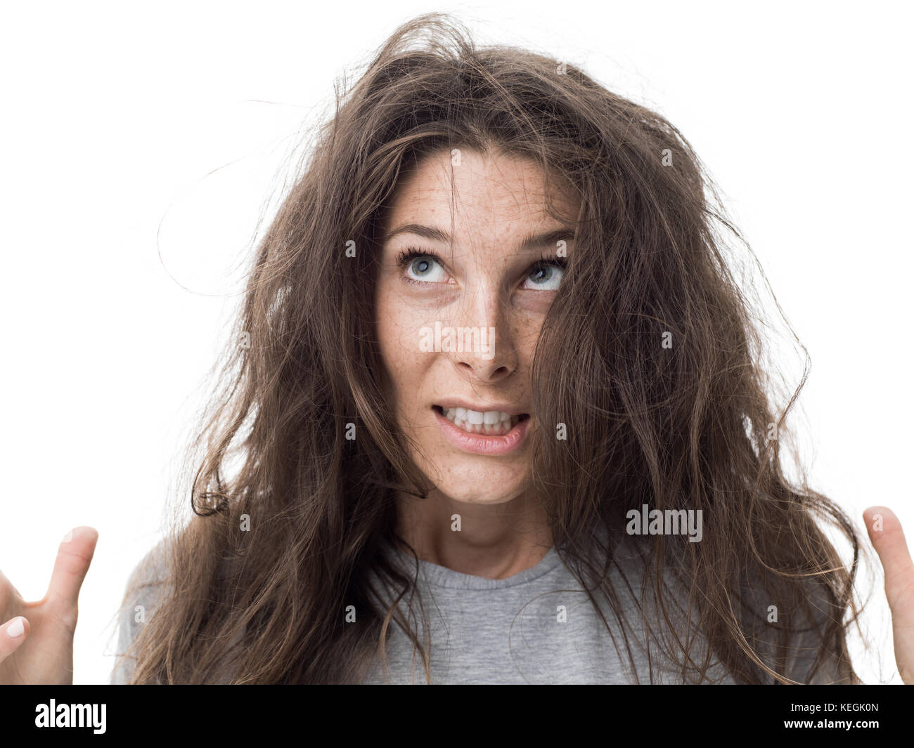 Angry young woman having a bad hair day, her long hair is messy and ...