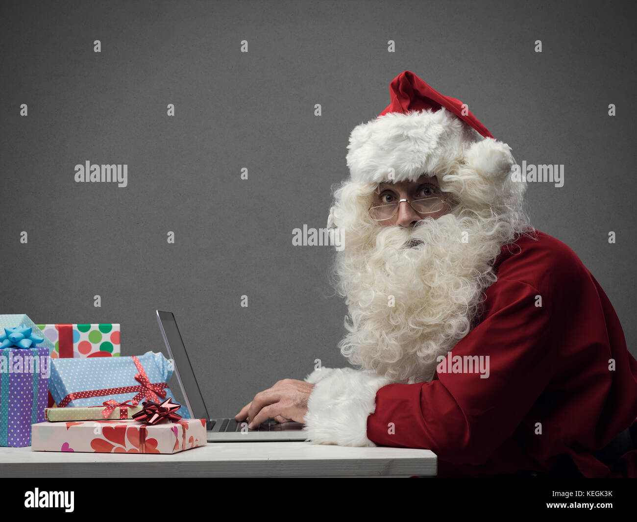 Santa Claus connecting and working online with his laptop, he is ...
