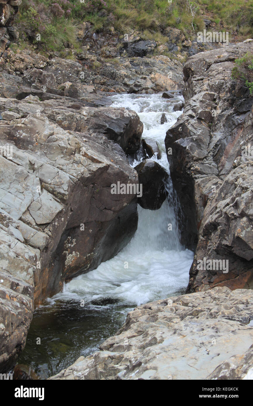 A rock wedged between two stone faces with water flowing against it ...
