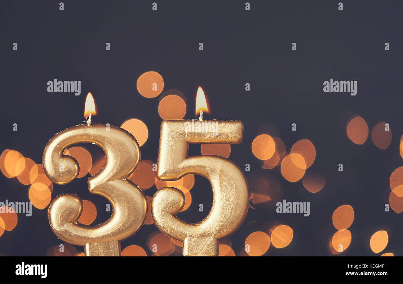 Gold number 35 celebration candle against blurred light background ...