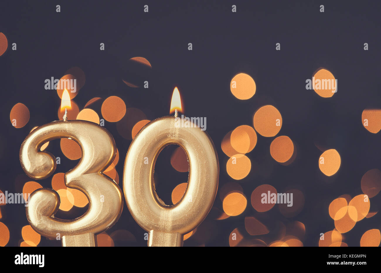 Gold number 30 celebration candle against blurred light background ...