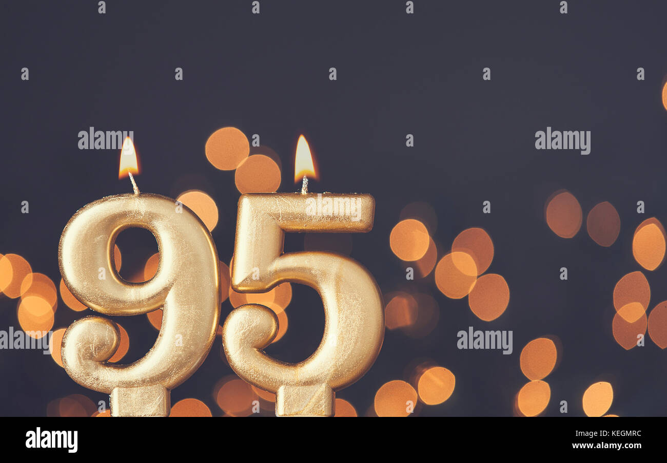 Gold number 95 celebration candle against blurred light background ...