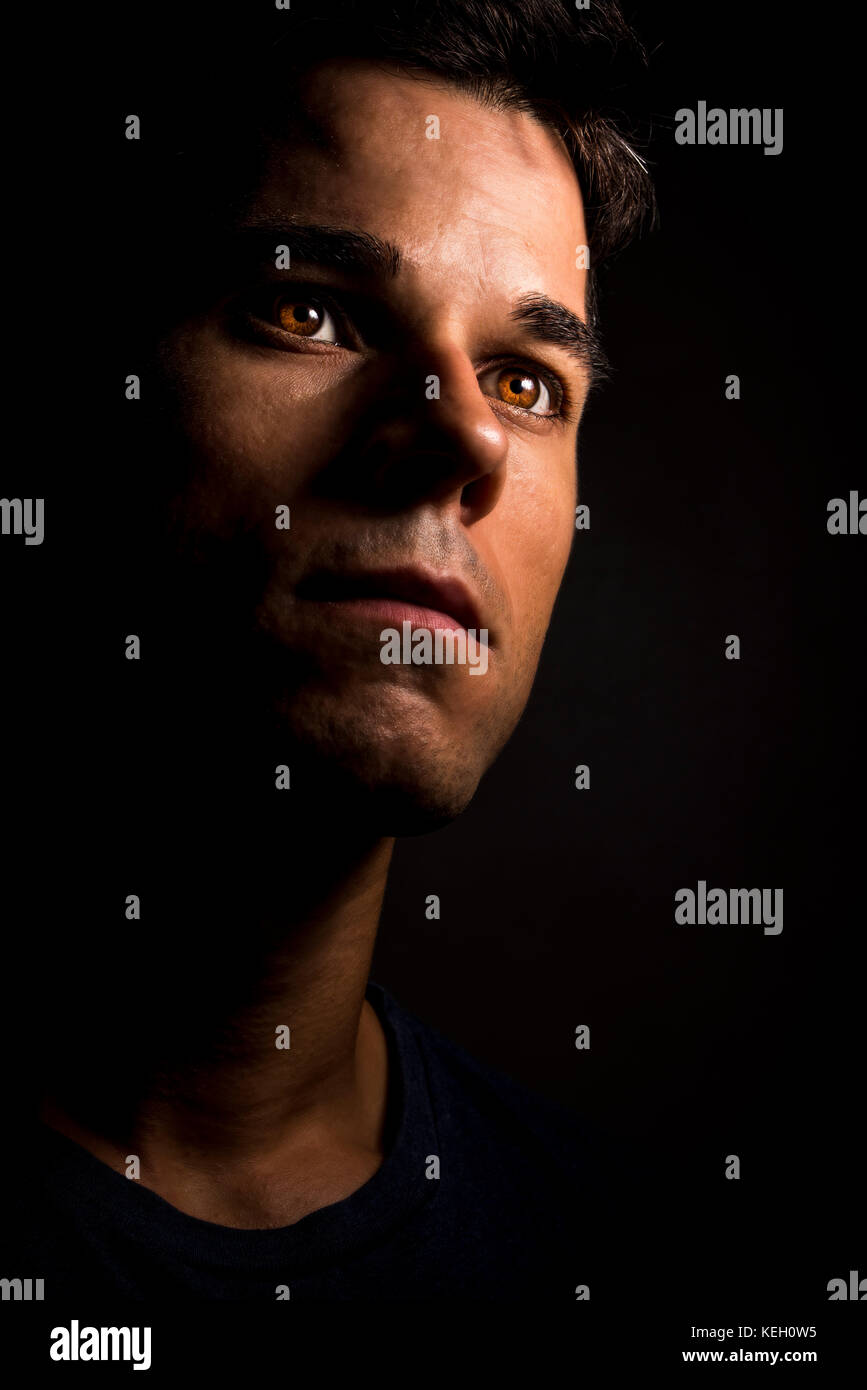 Man portrait looking up and dark background with light coming from the ...