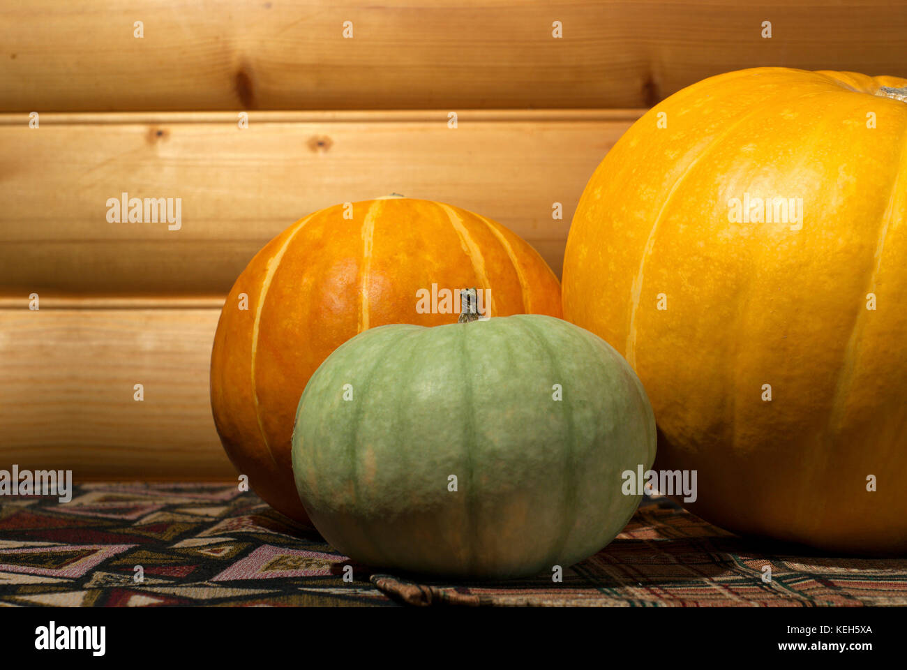 three different-colored pumpkins of different sizes on a table on a ...