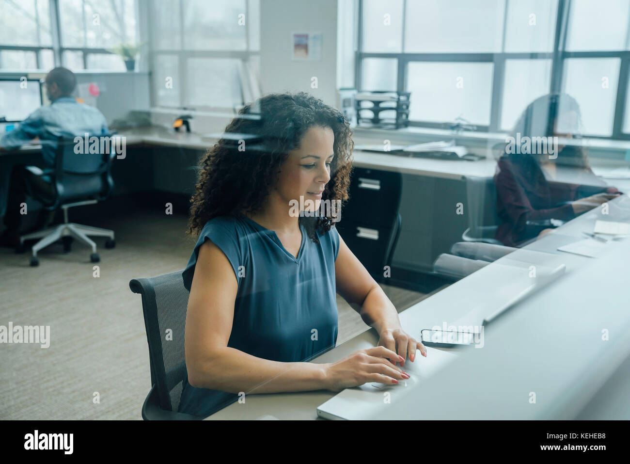 Businesswoman working in office behind window Stock Photo - Alamy