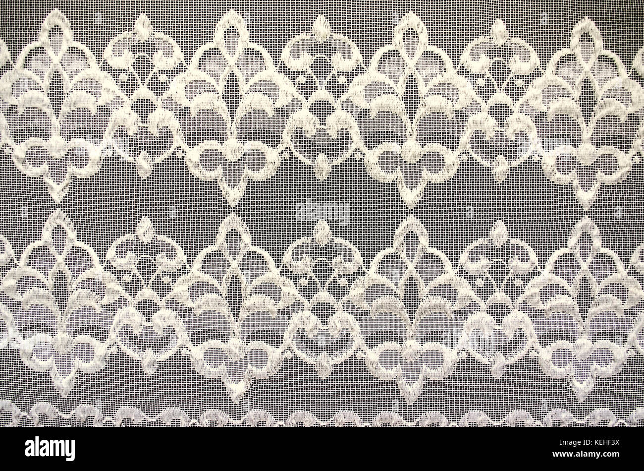 White ornament embroidered on a fine mesh fabric stretched over a black ...