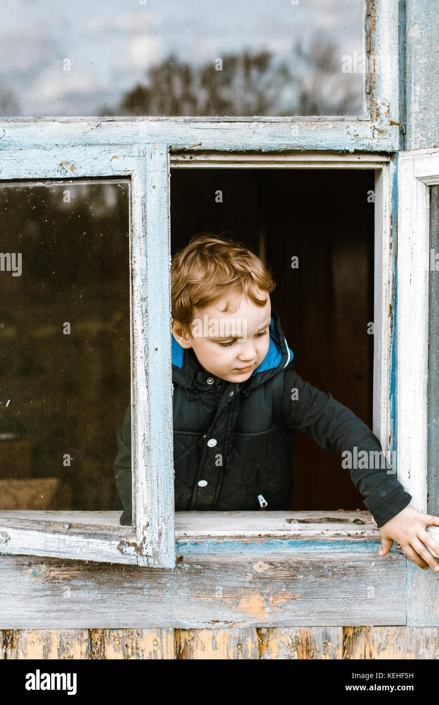 Caucasian boy opening window Stock Photo - Alamy