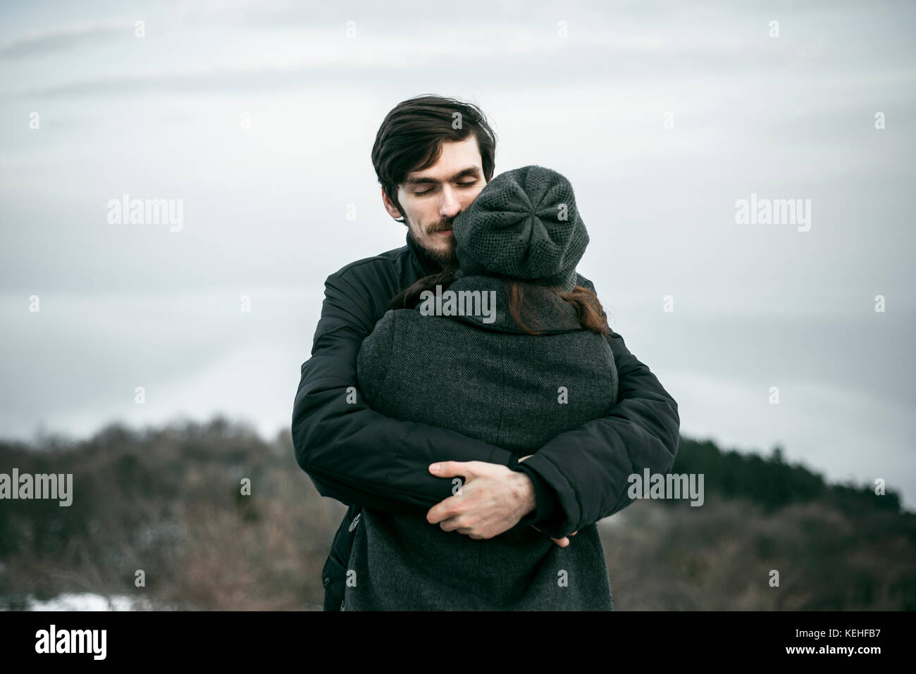 Caucasian couple hugging on hill Stock Photo - Alamy