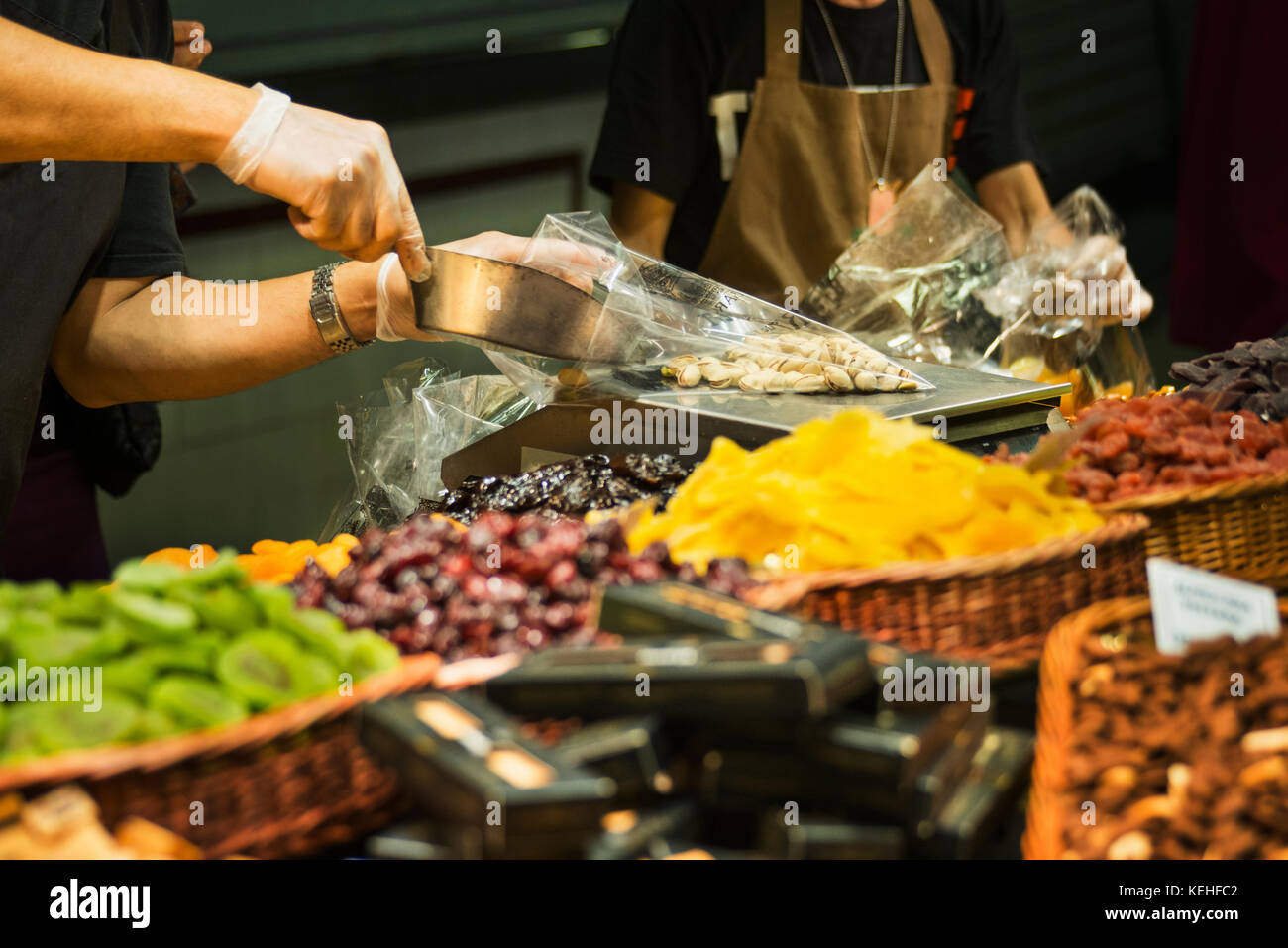 Worker scooping nuts into plastic bag at market Stock Photo - Alamy