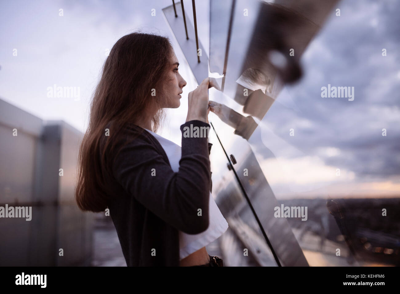 Curious Caucasian woman peering over glass wall at scenic view Stock ...