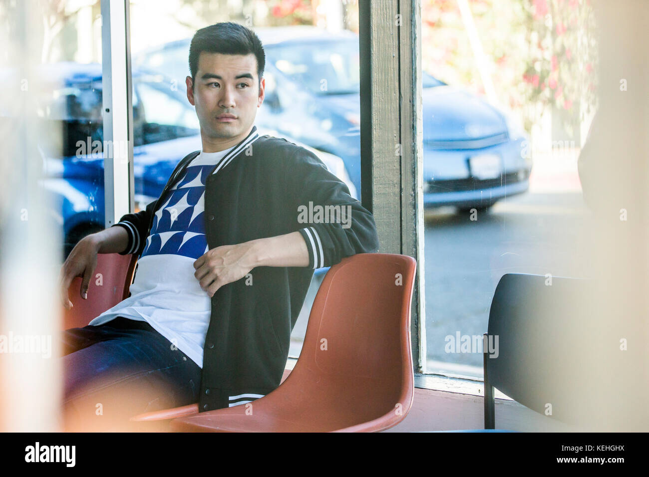 Serious Chinese man sitting in chair near window Stock Photo - Alamy